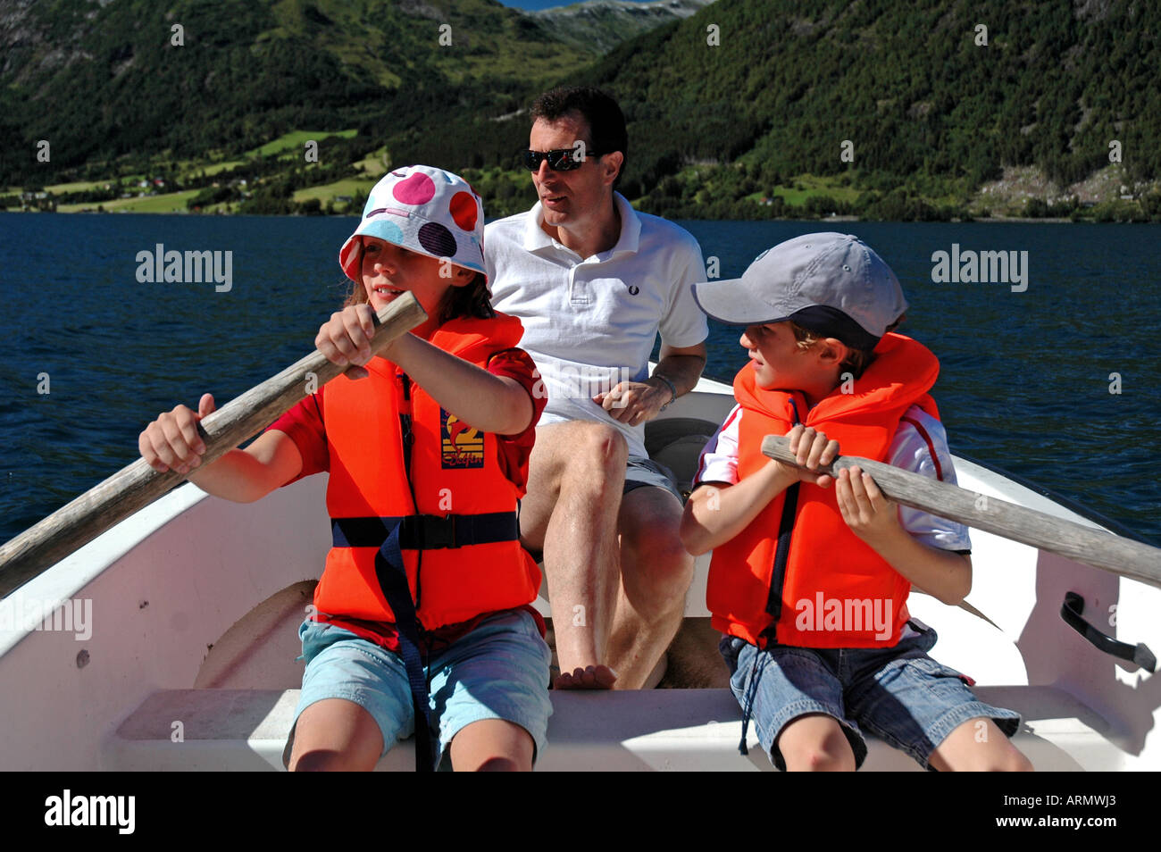 children rowing a dingy or row boat on a lake during the summer ...