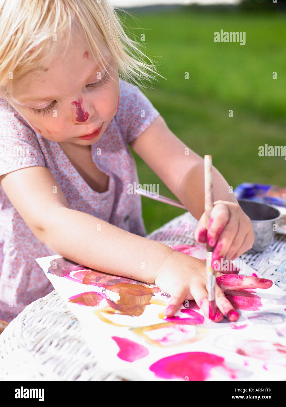 Little girl painting in a green field Stock Photo - Alamy
