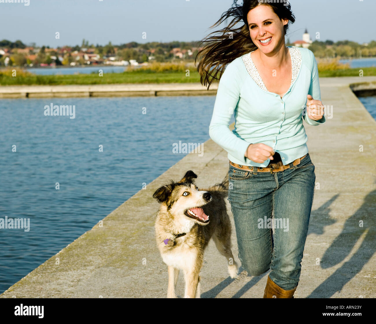Woman running with dog by a lake Stock Photo - Alamy