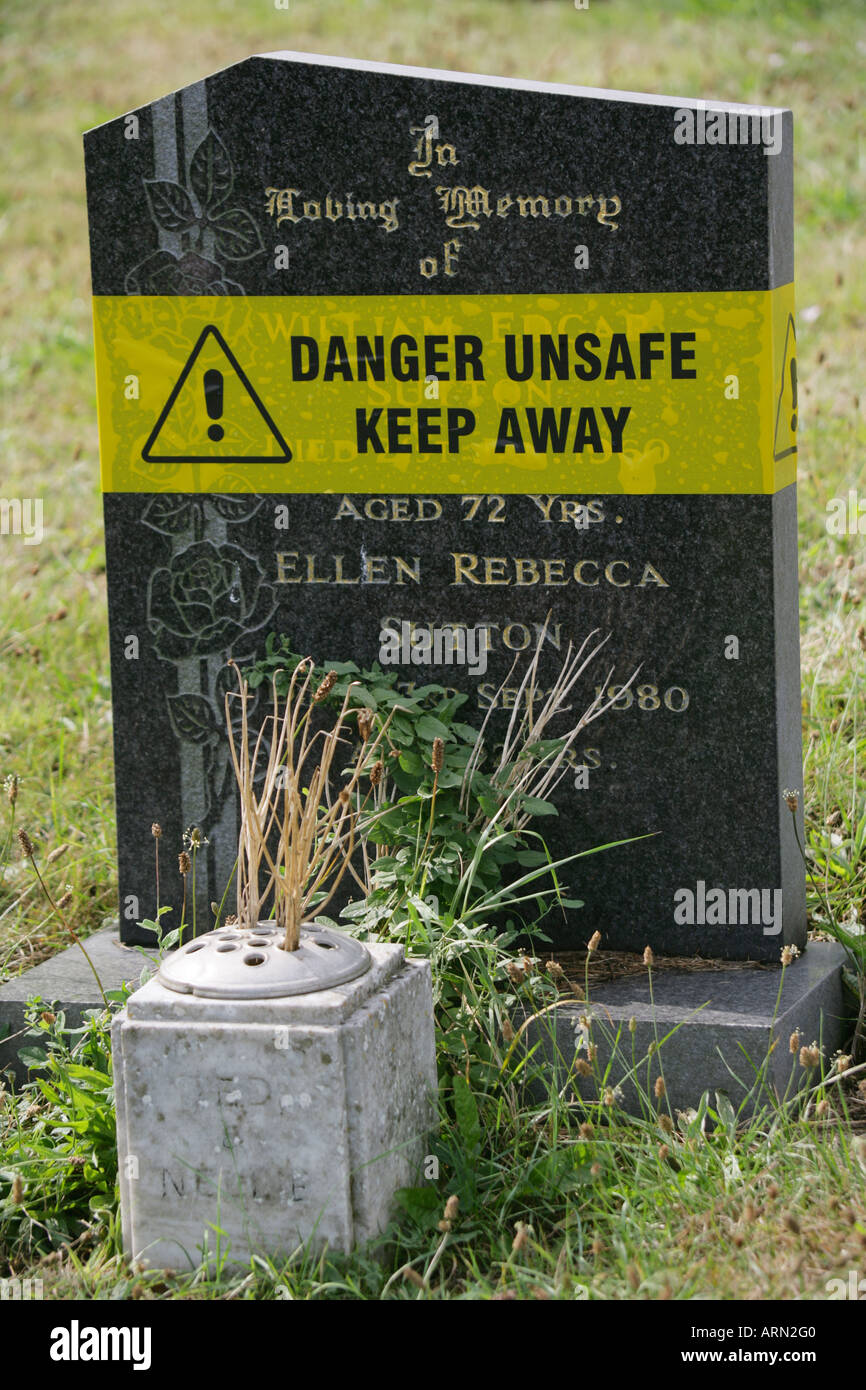 Unsafe headstone in cemetary wrapped with "Warning" yellow tape, Essex ...