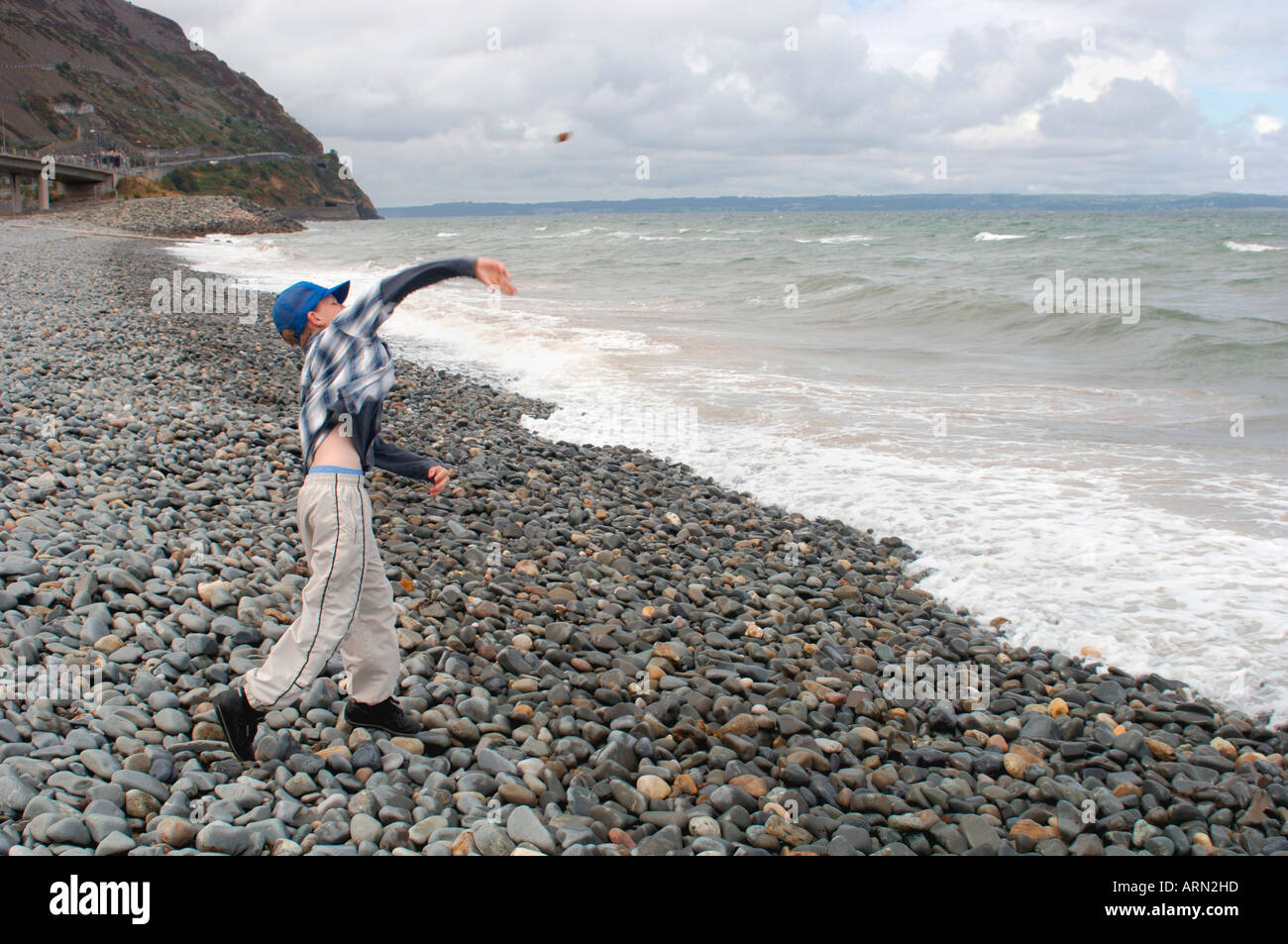 Boy Throwing Stones Into The Sea Stock Photo - Alamy