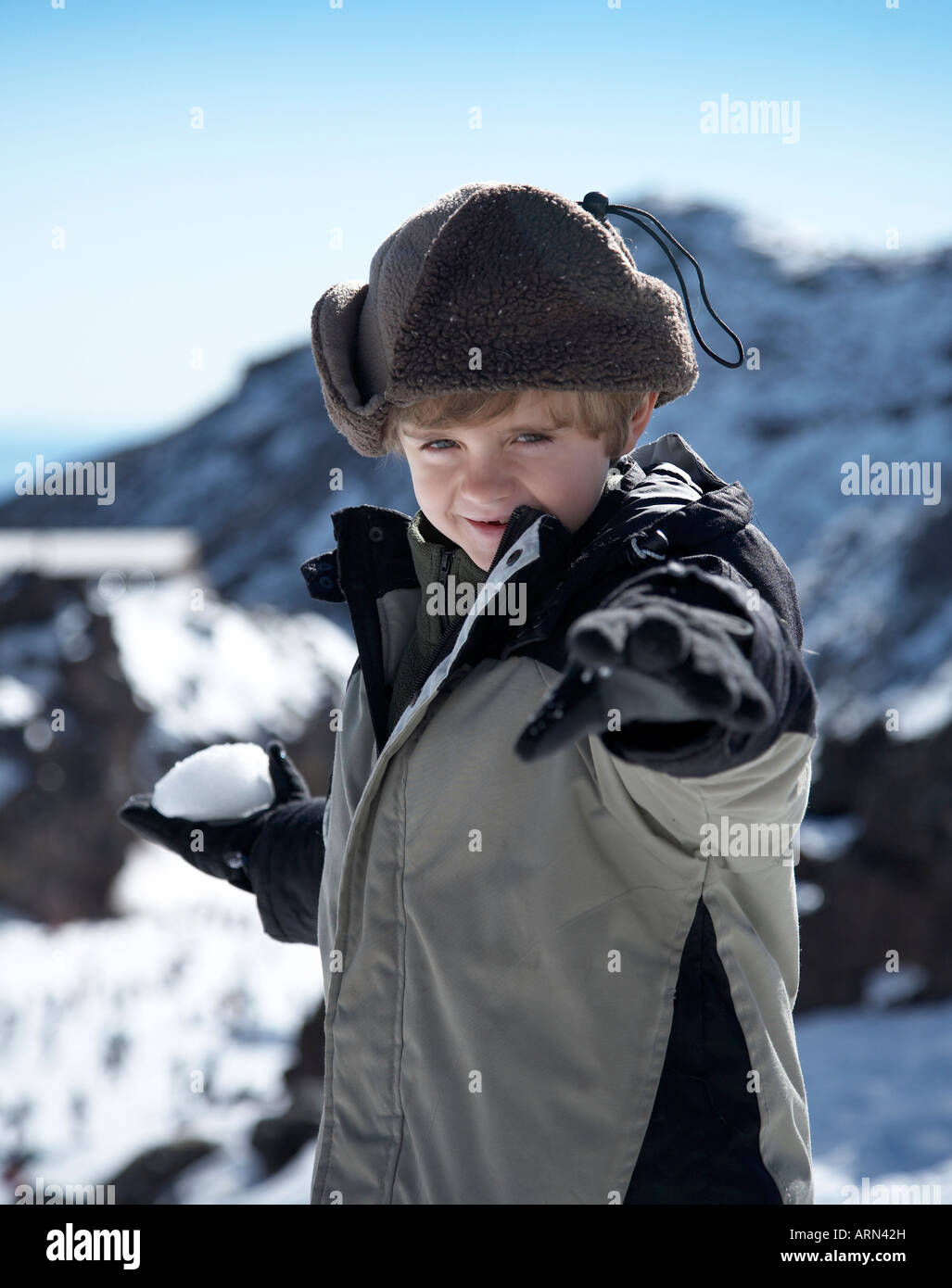 Child 7 wrapped up against cold throwing a snowball mr Stock Photo - Alamy