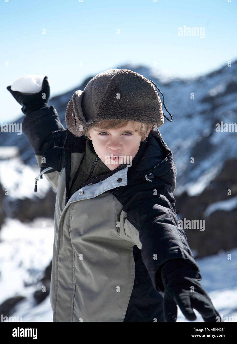Child wrapped up against cold throwing a snowball mr Stock Photo - Alamy