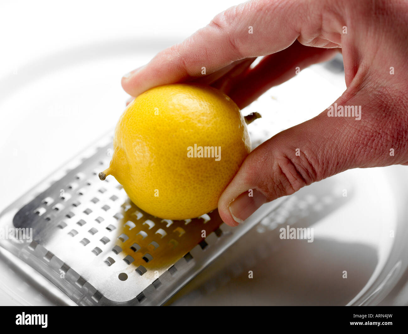 lemon being grated on lemon zester by person Stock Photo - Alamy