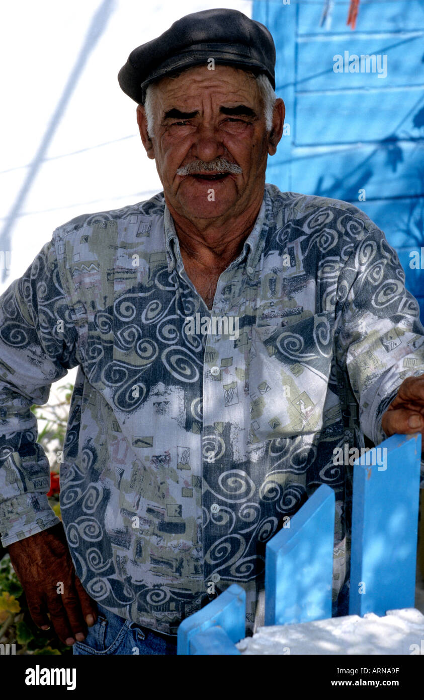 Local man relaxes at the blue painted gate of his home on the Greek ...