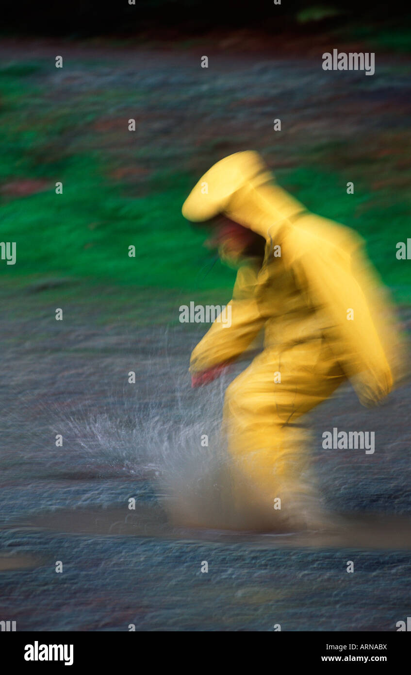 Boy in yellow raincoat kicks mud puddle, motion blur, British Columbia ...