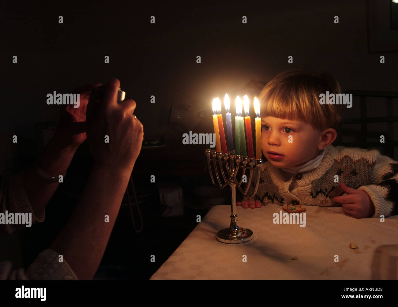 Small boy getting a picture taken as he lights the Hanukkah Menorah ...