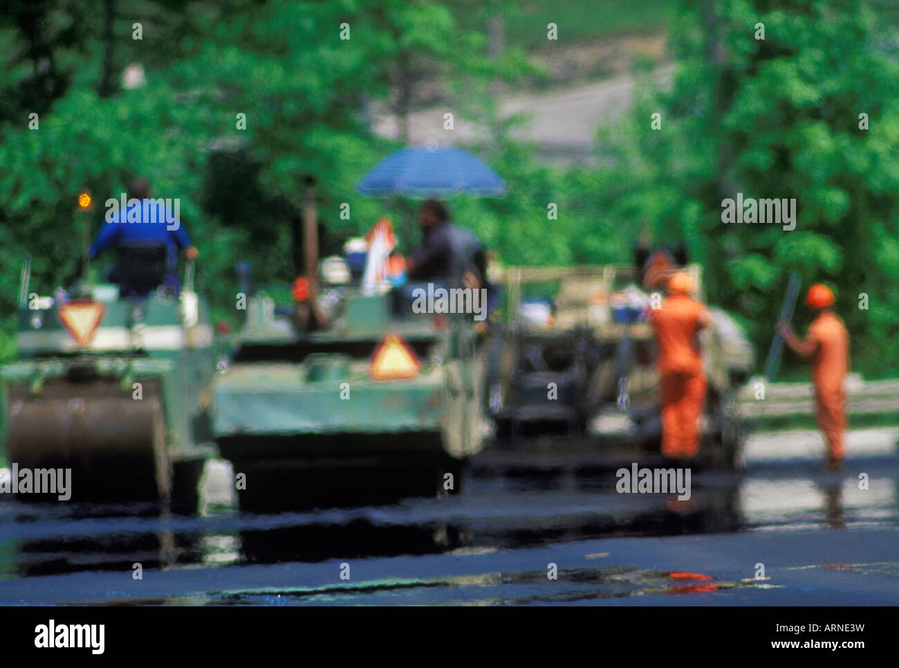 Road construction crew at work building a new road, blurred by heat ...
