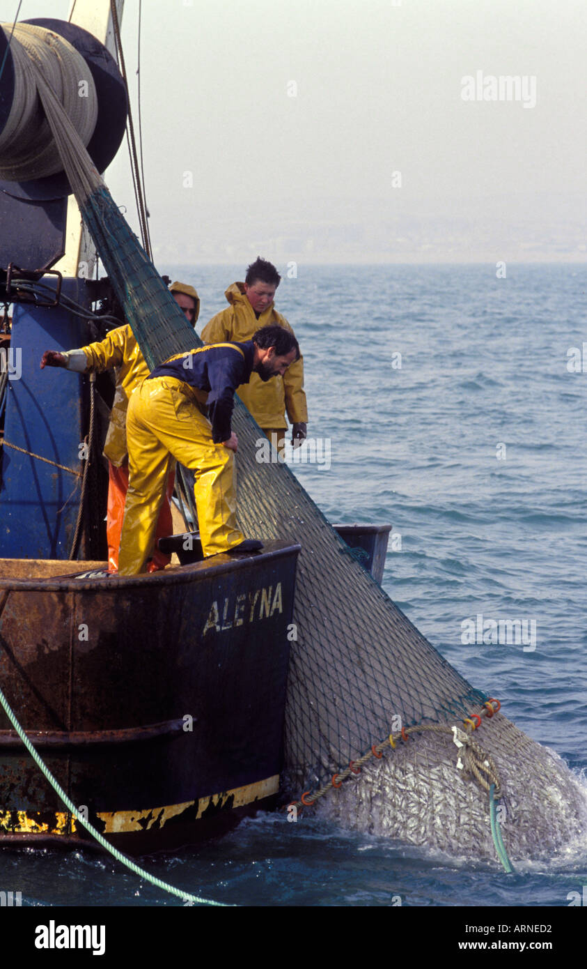 The fishing nets full of fish are hauled onboard a fishing trawler in ...