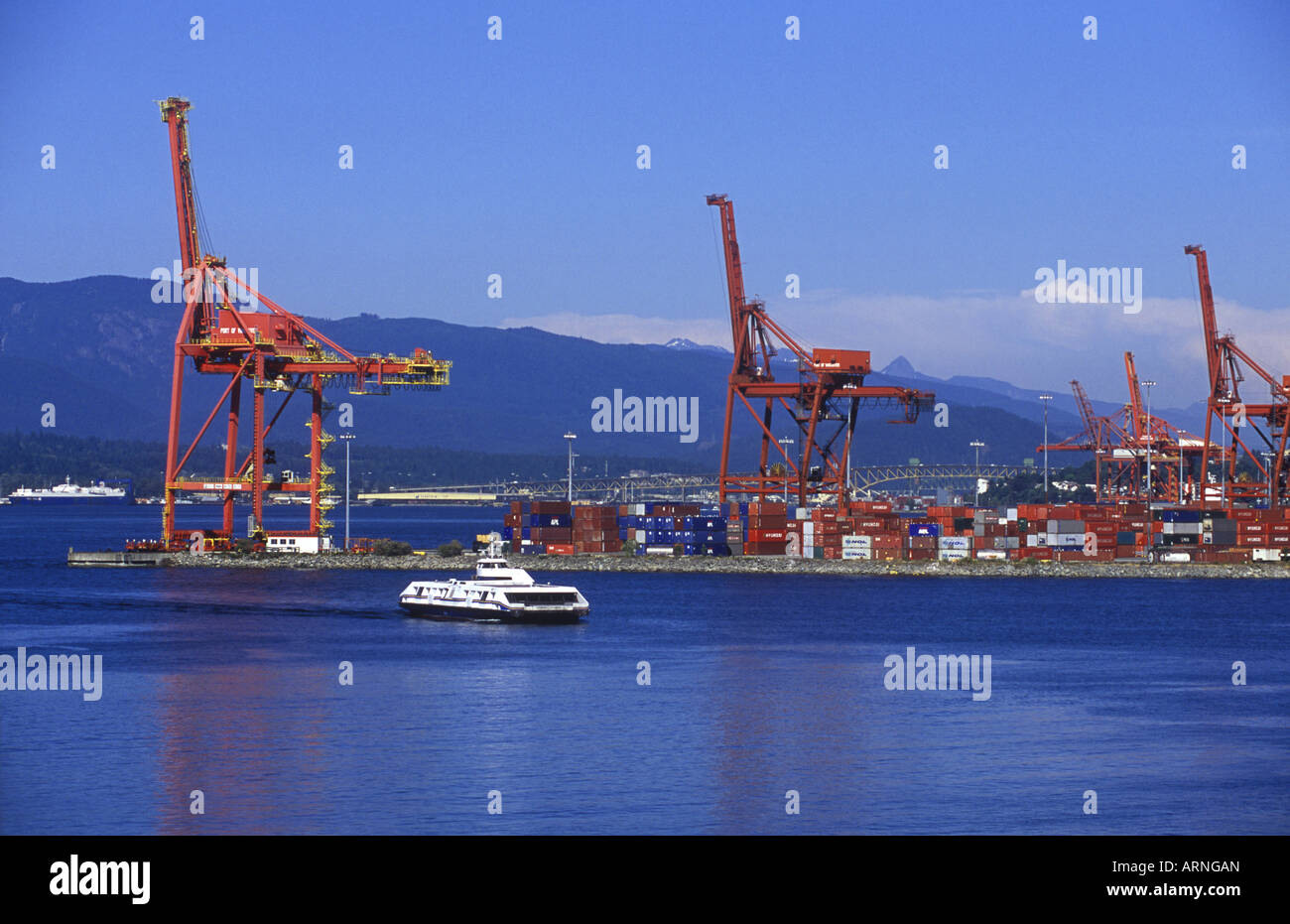 Seabus crossing the Burrard Inlet with cargo ship cranes beyond. The ...