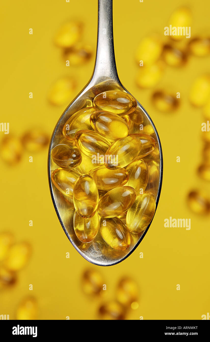 a spoon full of supplements set against yellow background Stock Photo ...