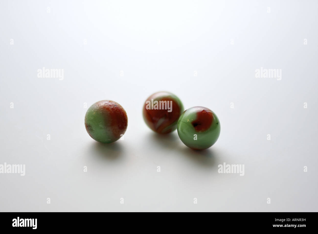 Three green and red glass marbles Stock Photo - Alamy