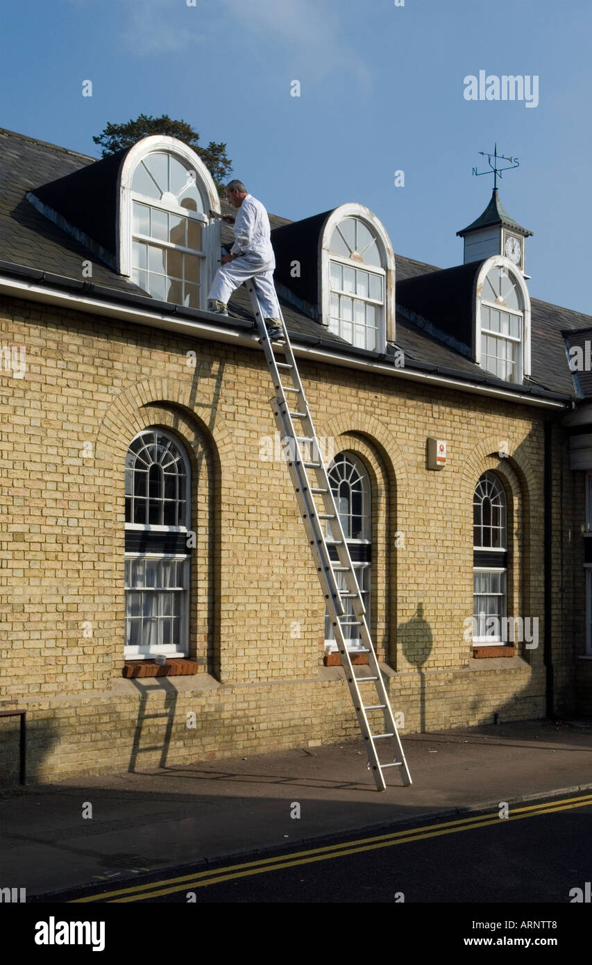 MAN UP A LADDER PAINTING A WINDOW FRAME SAFFRON WALDEN ESSEX Stock ...
