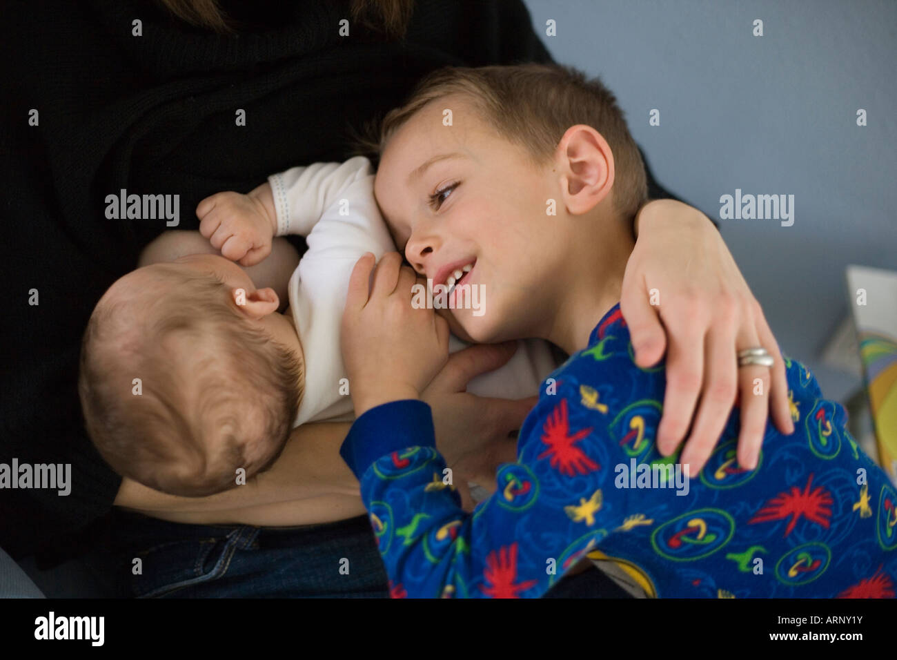 four year old brother hugs infant sibling while baby nurses Stock Photo ...