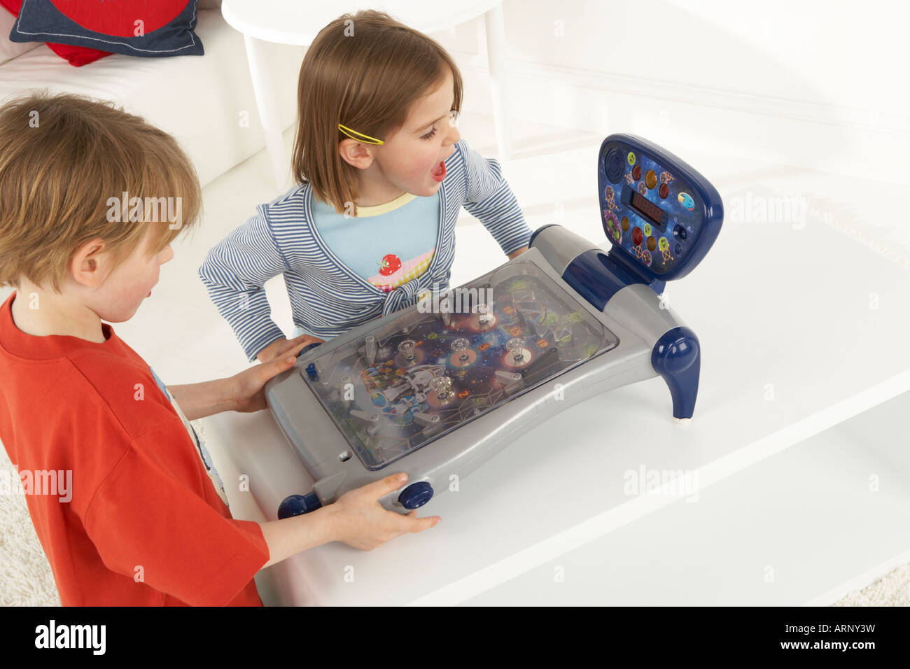A boy and a girl play at a table with a pinball game Stock Photo - Alamy