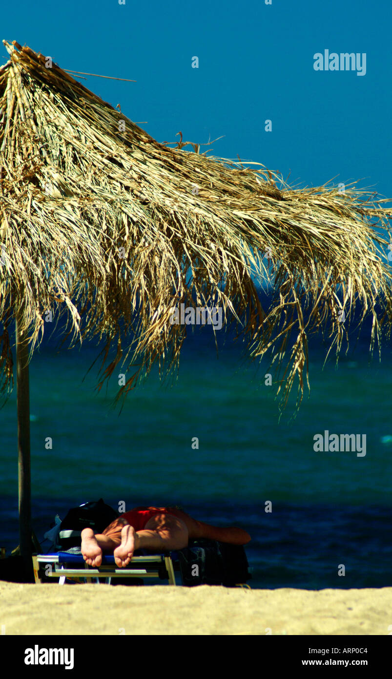 Feet sticking out from under grass parasol Stock Photo - Alamy