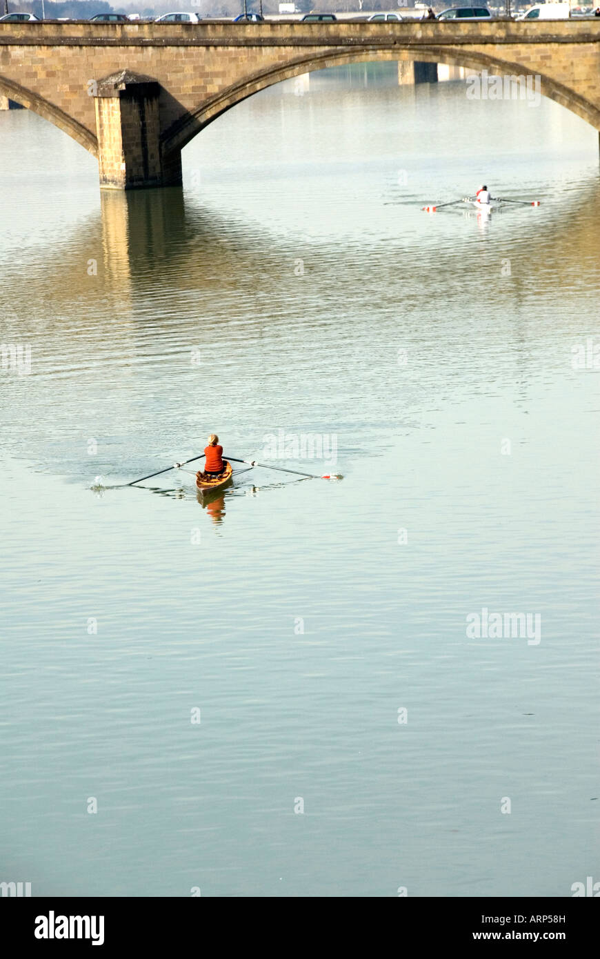 Two single skulls rowing boats on the Arno River Florence Tuscany with ...