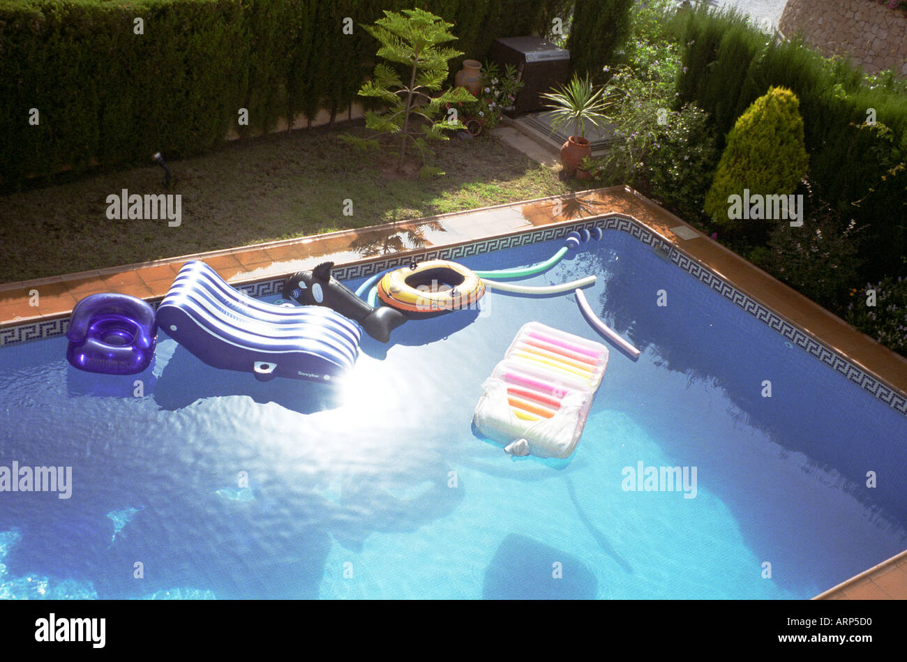 Bright blue swimming pool with inflatable pool toys in it, red tiles ...