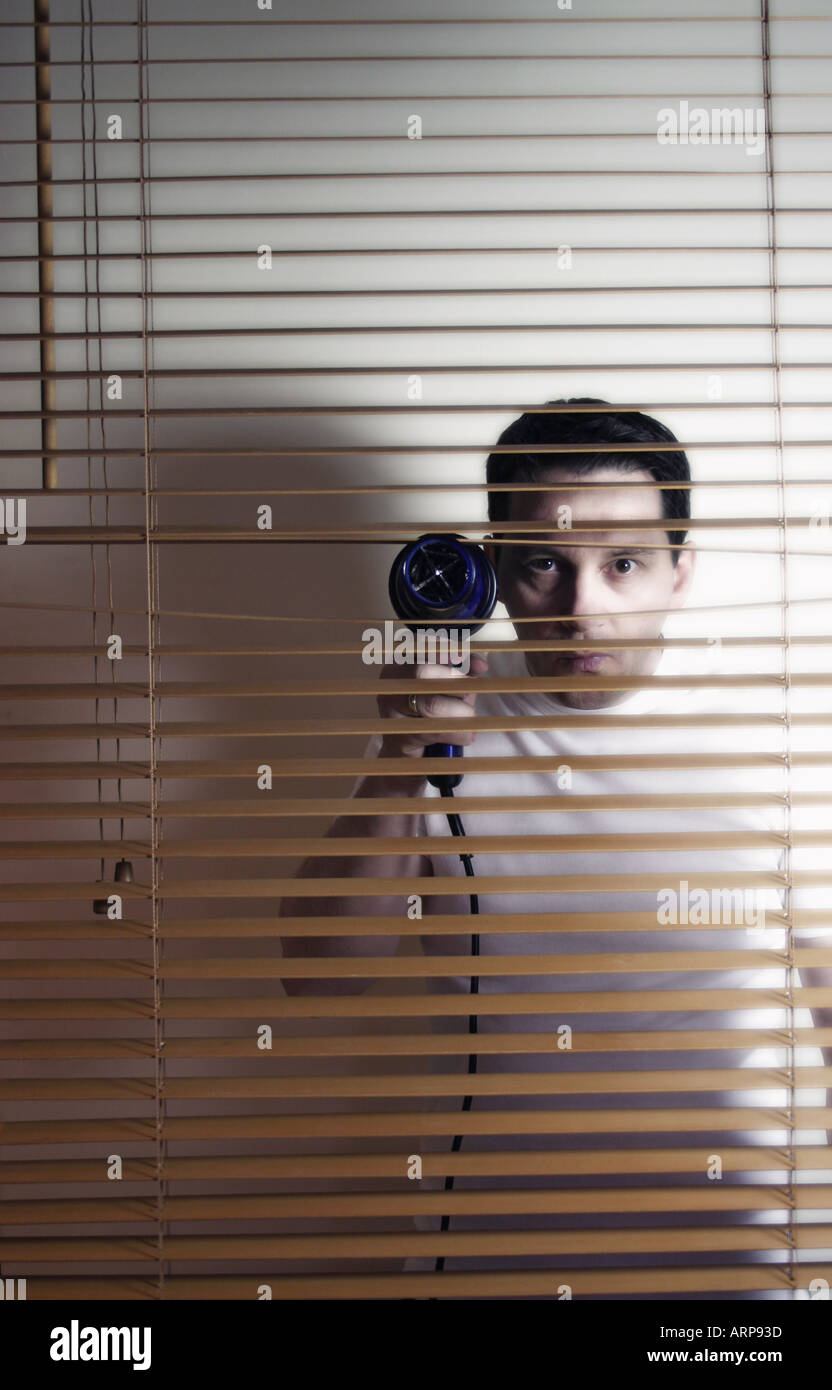 Man peering through window pointing his hair dryer Stock Photo - Alamy
