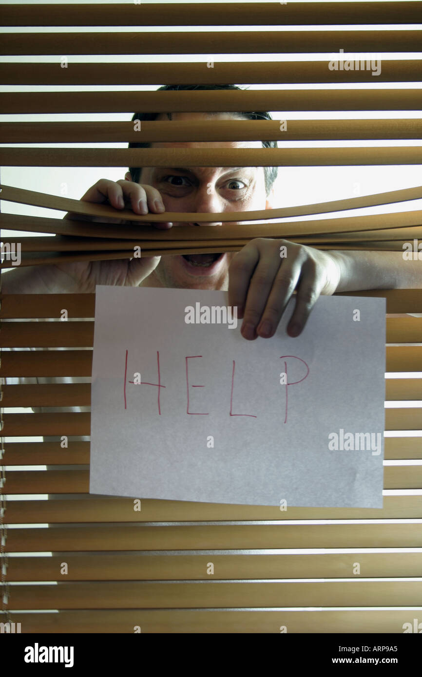 Man trapped behind window with help sign Stock Photo - Alamy