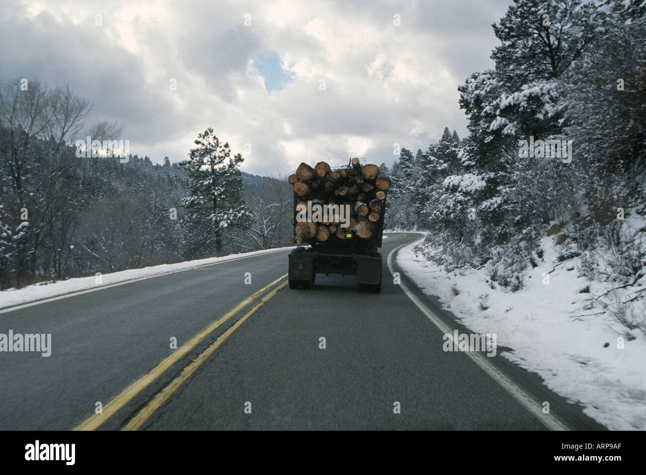 Logging truck with log load on two lane mountain highway in winter ...