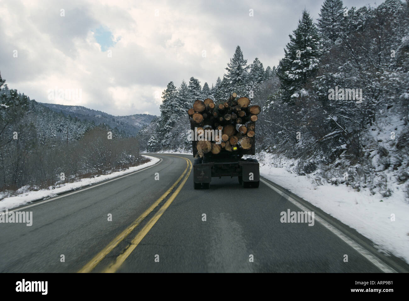 Logging truck with log load on two lane mountain highway in winter ...