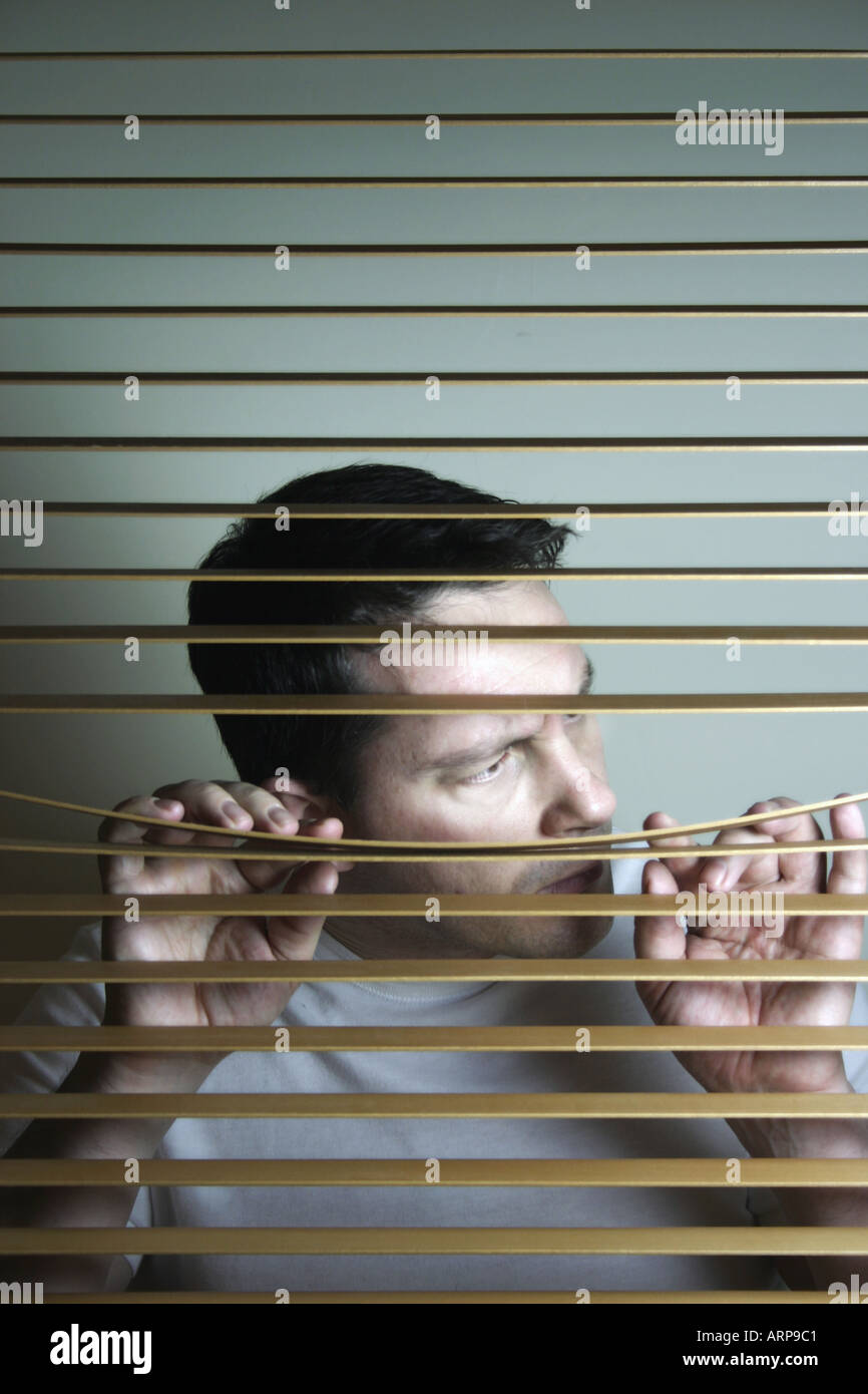 Man looking out from behind window blinds Stock Photo - Alamy