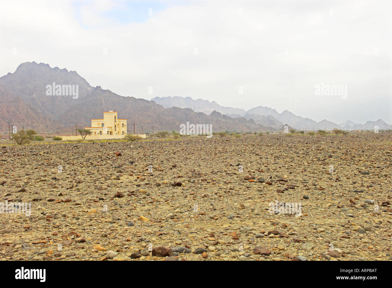 Pebbles in Wadi with typical view of mountains in background Oman ...