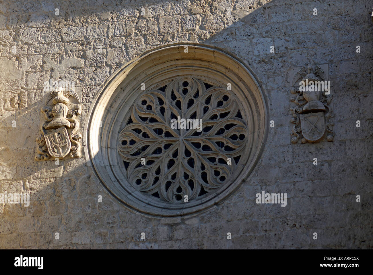 rosette in church facade franked by coat of arm sculpted in stone Stock ...