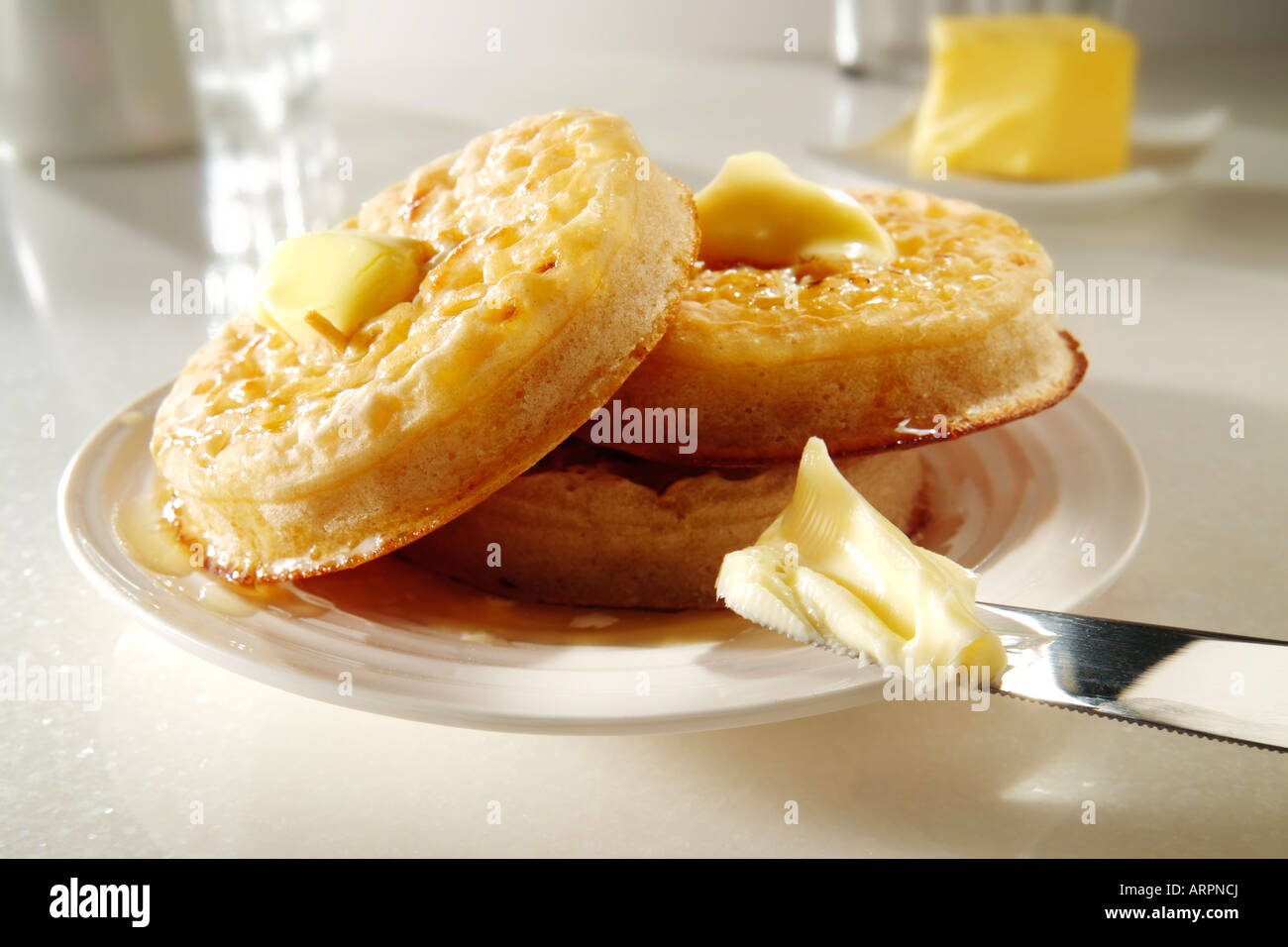 Traditional hot buttered toasted crumpets on a white plate on a table ...