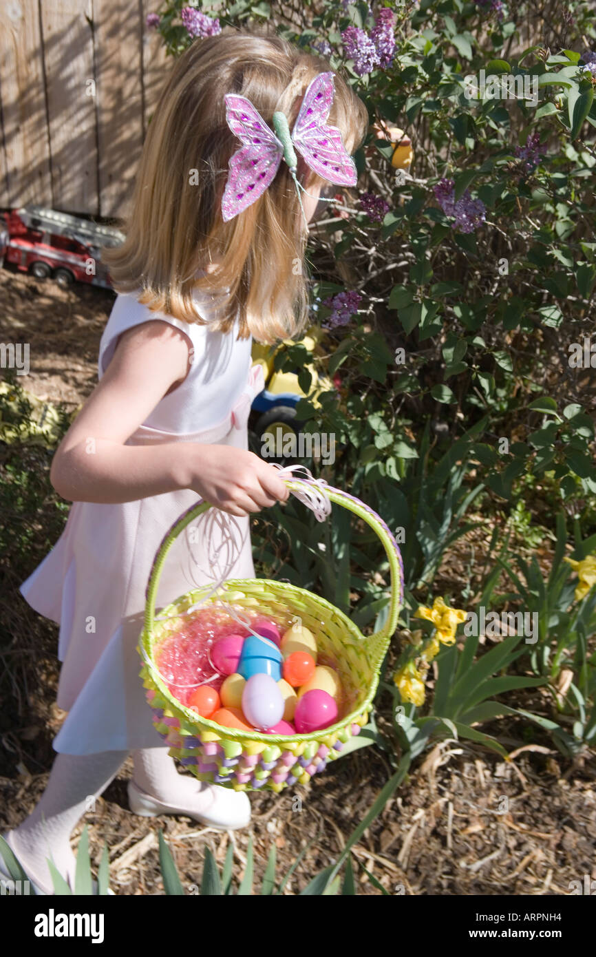 girl holding easter eggs in basket in backyard during Easter Egg hunt ...