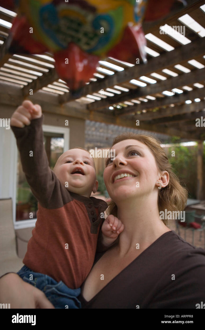 toddler reaching up to touch a ceramic sun hanging on porch Stock Photo ...