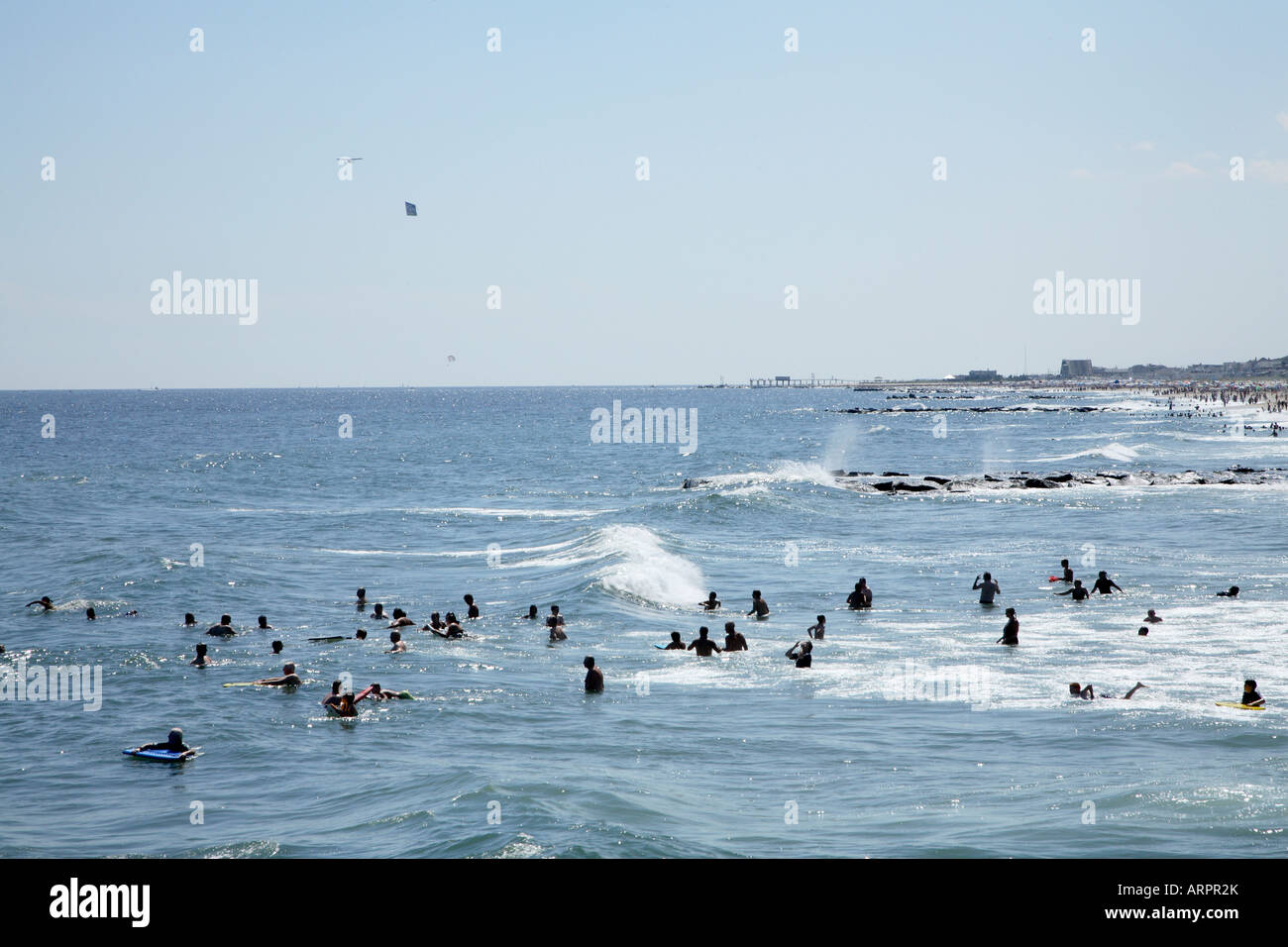 People wading and playing in shallow breaking wave on oceans edge ...