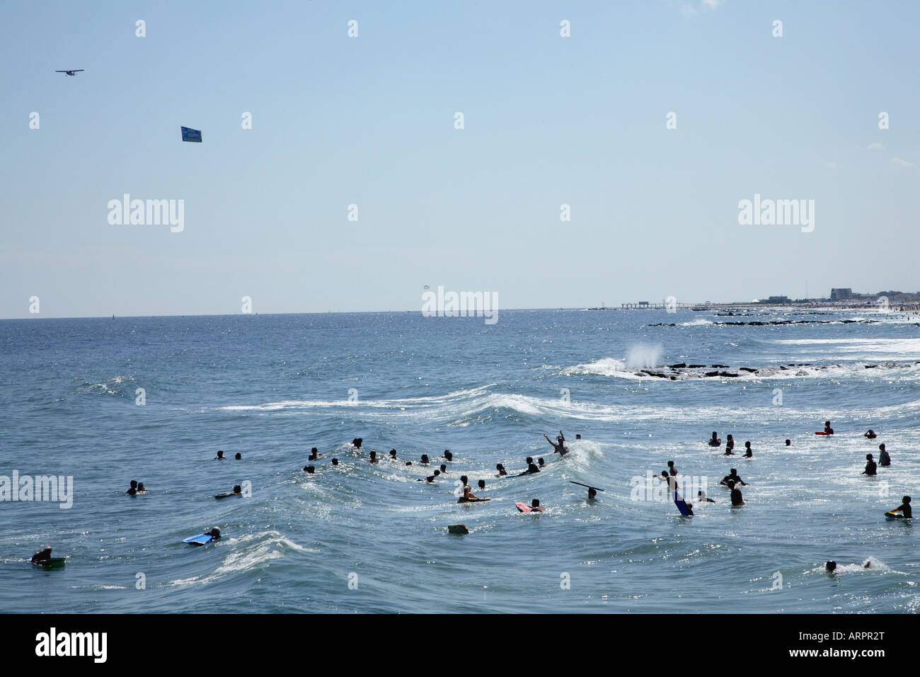 People wading and playing in shallow breaking wave on oceans edge ...