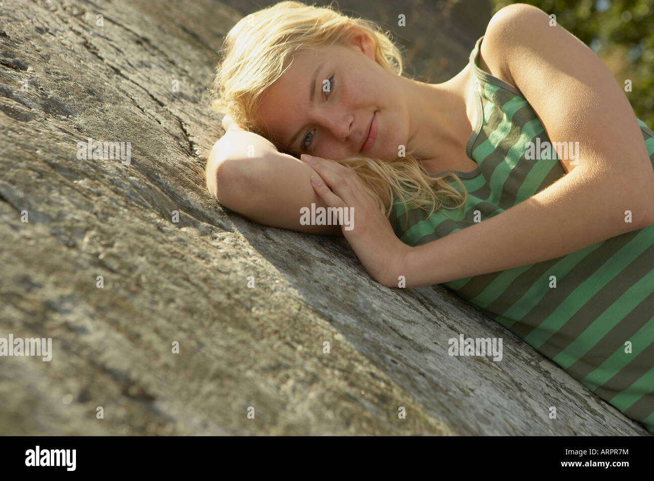 Young woman lying down on rocks Stock Photo - Alamy