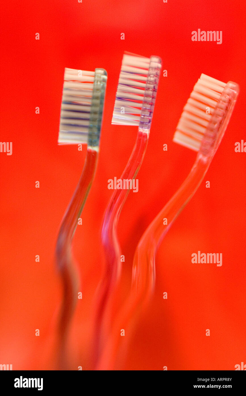 Three toothbrushes against a red background Stock Photo - Alamy