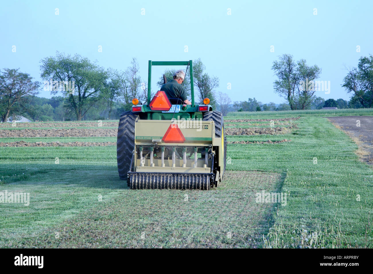 Man driving tractor pulling a slitting seeder Stock Photo - Alamy