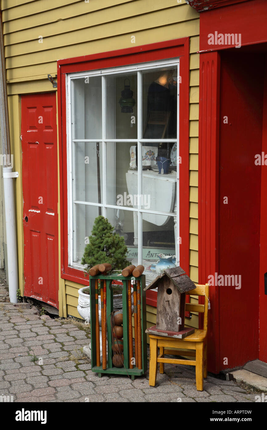 Bright red and yellow painted shop front with a small chair with bird ...
