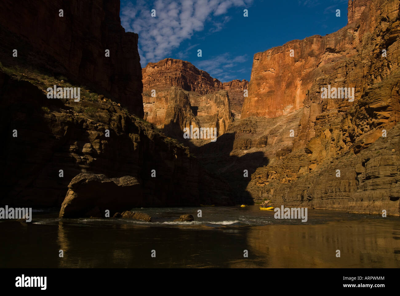 Large rock in the Colorado River with rafters beyond dwarfed by the ...