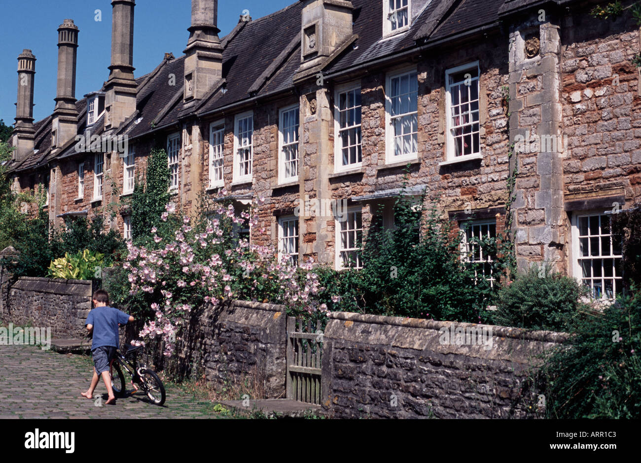 Boy pushing a bicycle along the cobblestones of Vicars Row Wells ...