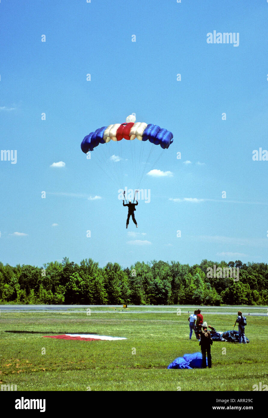 Red white and blue parachute descending from blue sky to land on target ...