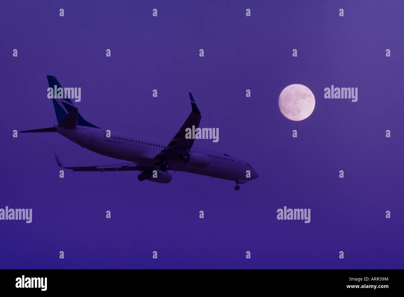 Airplane flying past full moon at night Stock Photo - Alamy