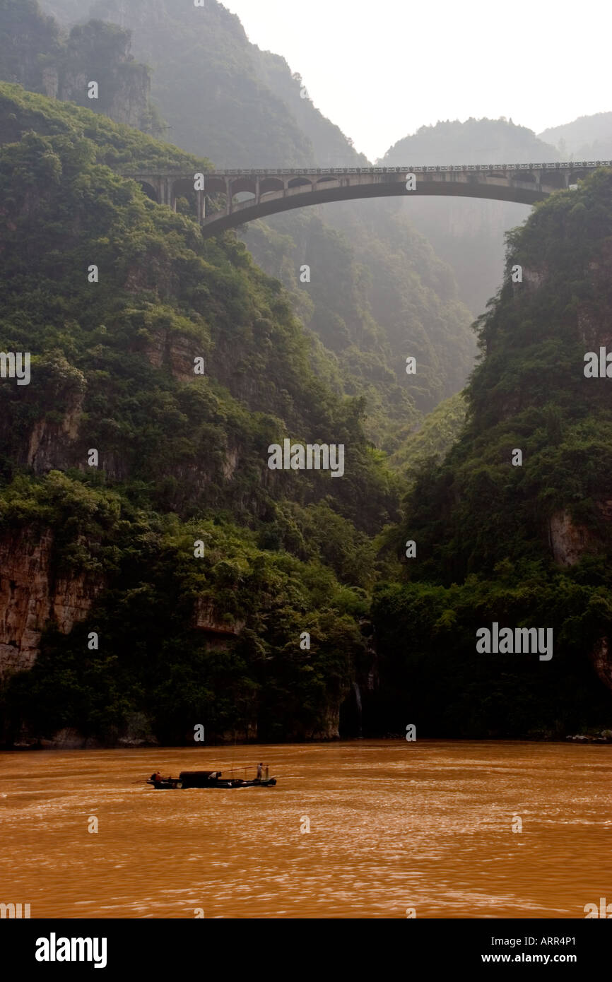 Impressive bridge over a narrow gorge with a small Chinese boat sailing ...