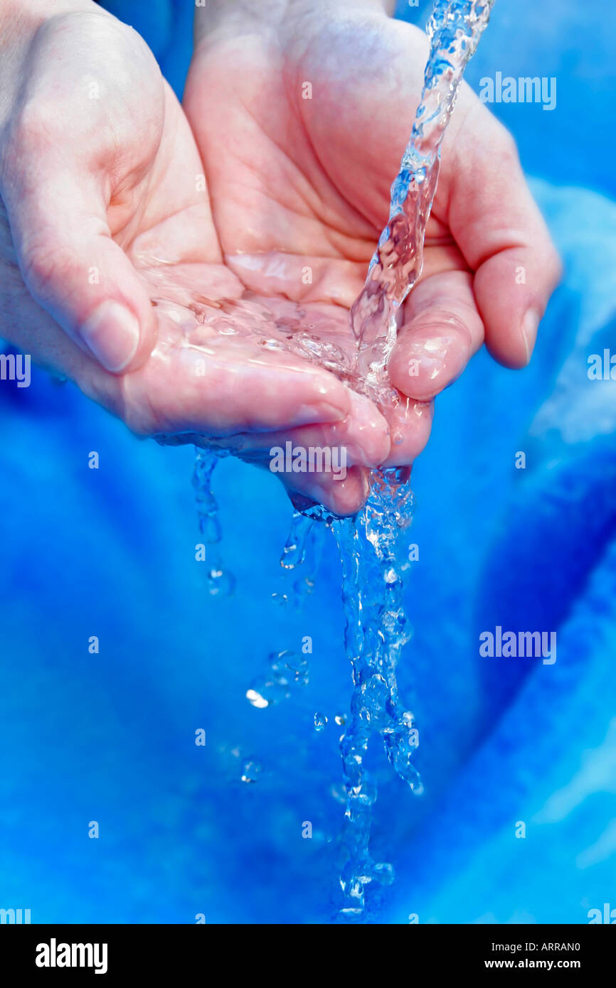 Mineral water falling to hands Stock Photo - Alamy
