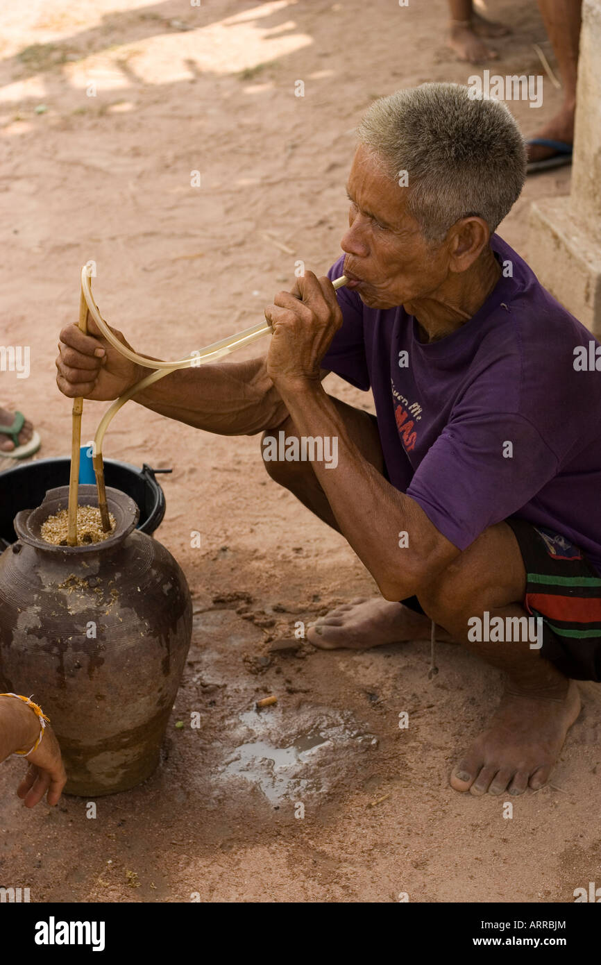 Men drinking rice alcohol through straws out of a clay pot celebrating ...