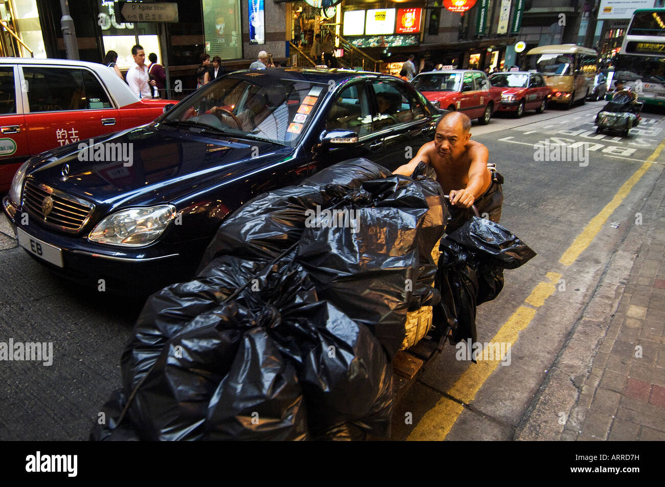 Workers compete for space with luxury cars as they push trollies of ...