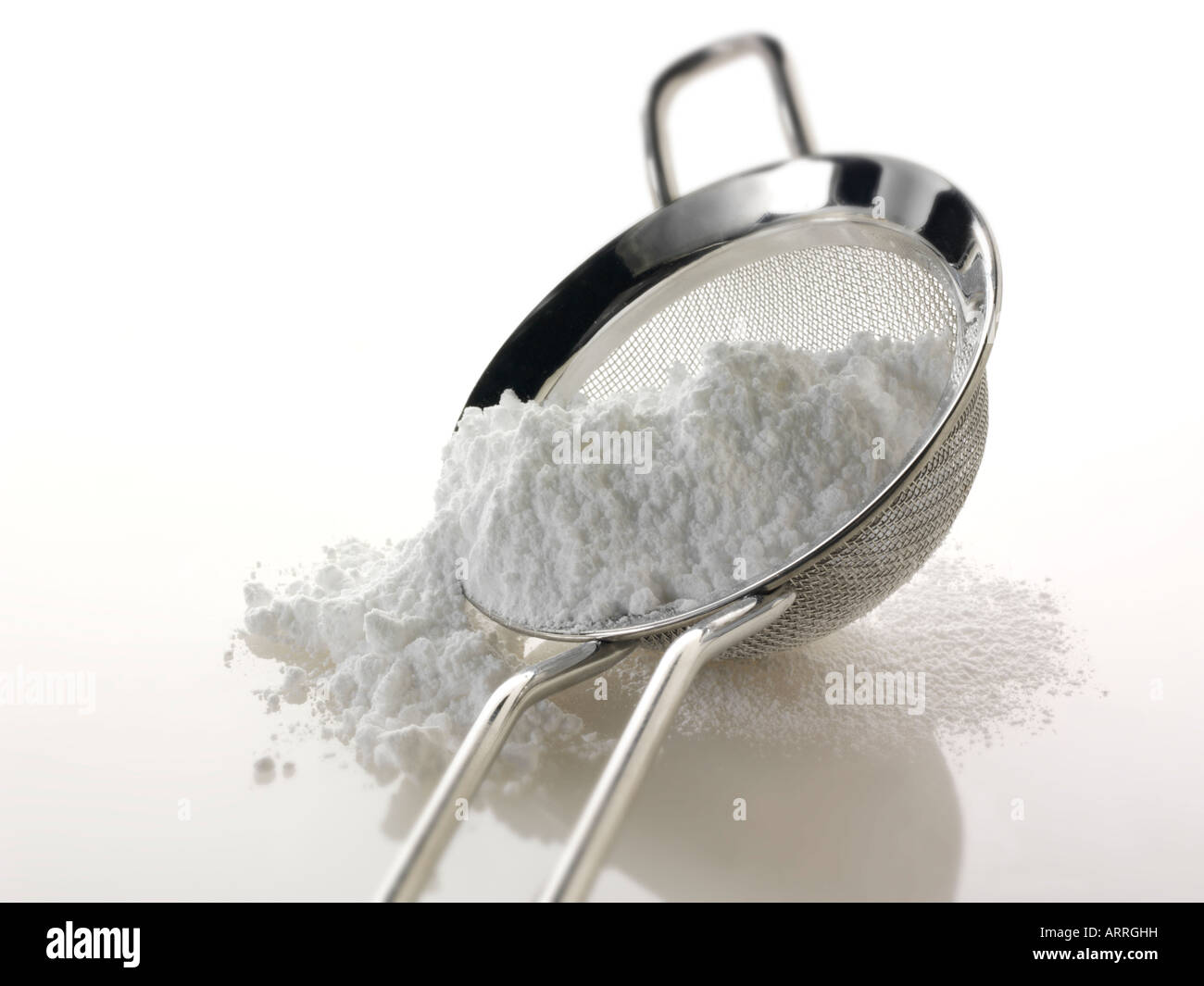 Icing sugar on a sieve against a white background Stock Photo - Alamy