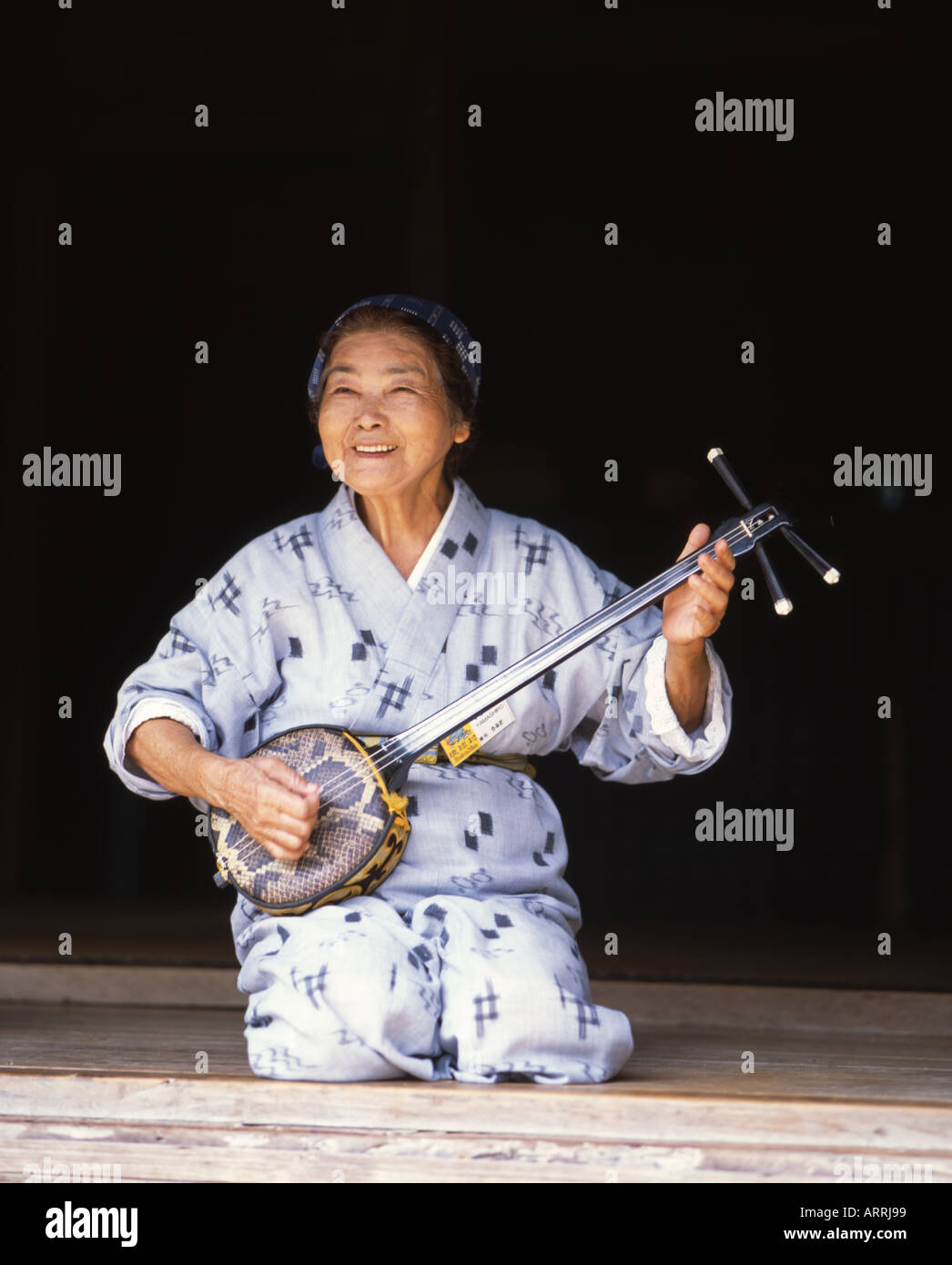 Elderly Okinawan lady plays the sanshin ( shamisen ), the tradtional 3 ...