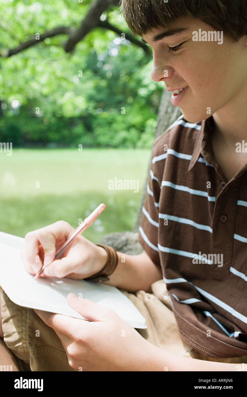 Boy writing in a notebook Stock Photo - Alamy