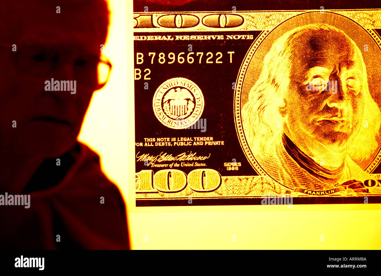 man examining an enlarged negative display of a one hundred dollar bill ...